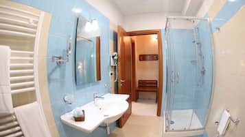 Casa de banho com cabine de duche envidraçada, lavatório, espelho e porta-toalhas.
