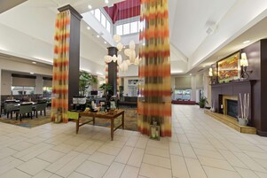 Um hall amplo com tetos altos, área de estar central e lareira.