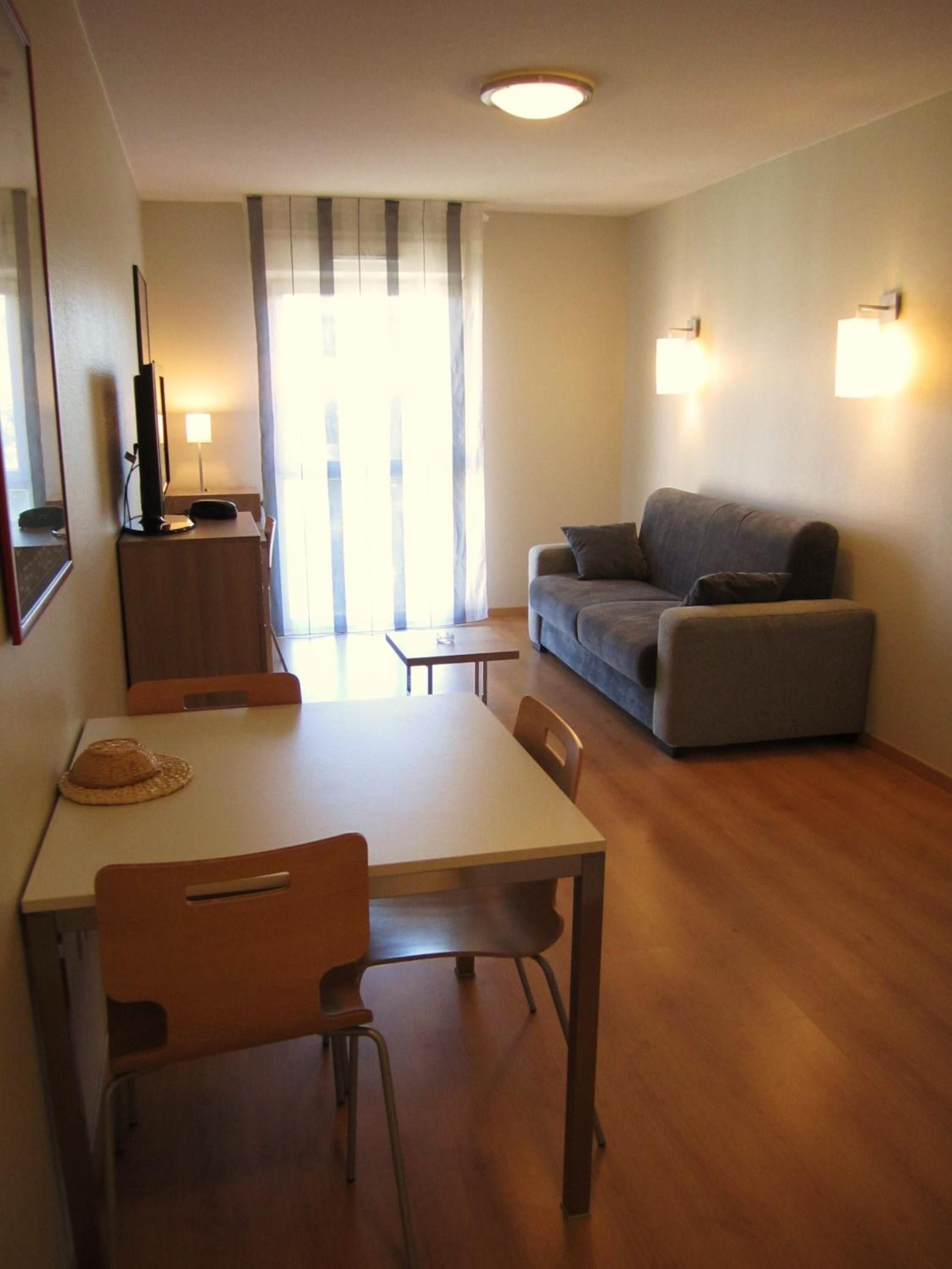 Um quarto com mesa de jantar, cadeiras, sofá e televisão.