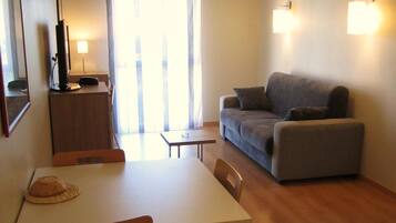 Um quarto com mesa de jantar, cadeiras, sofá e televisão.