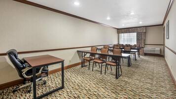 Uma sala de conferências com uma mesa comprida e cadeiras, piso coberto de carpete e uma janela com cortinas.