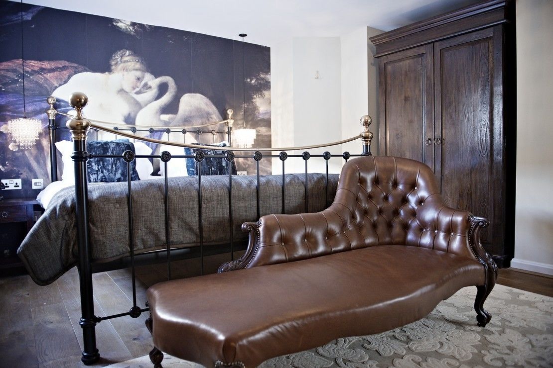 Quarto com cama, chaise longue, uma pintura grande e um guarda-roupa.