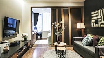 Quarto de hotel moderno com televisão de tela plana, sofá, mesa de centro e escrivaninha com cadeira.