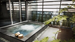 Uma banheira de hidromassagem moderna em ambiente interno, com vista para a paisagem urbana através de grandes janelas.