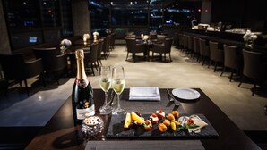 Espaço de restaurante com bar, mesas de jantar e vista para a cidade.