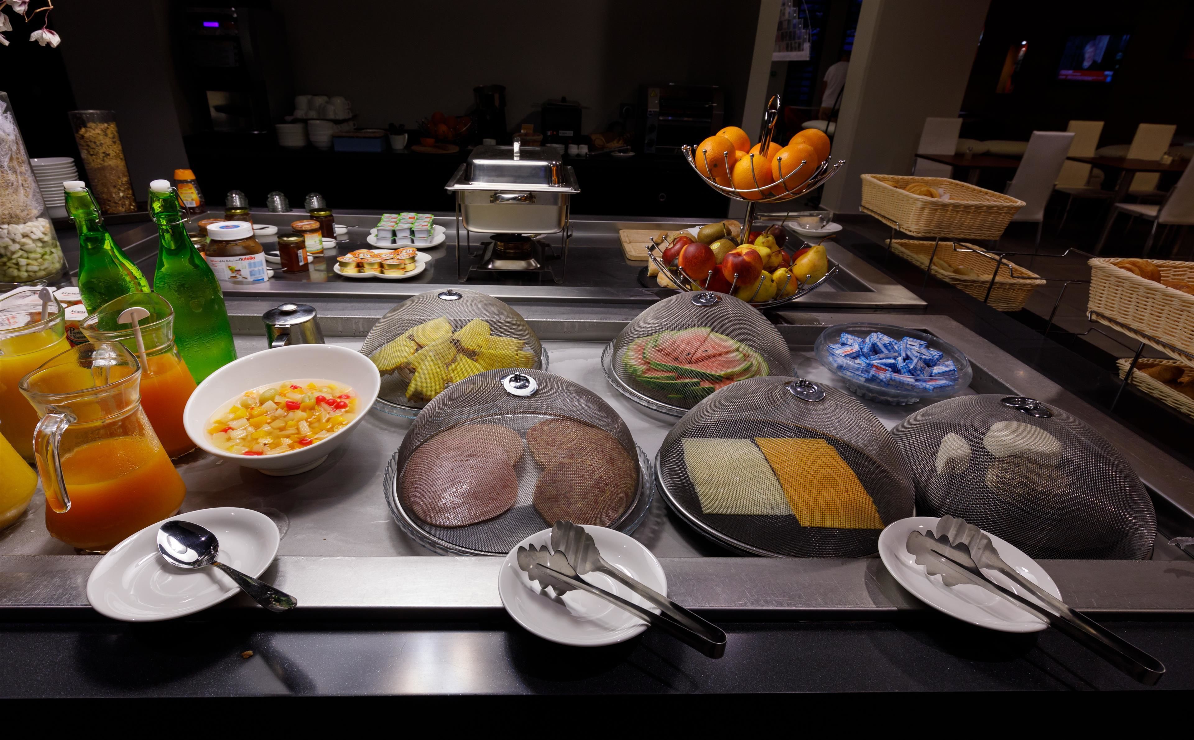 Buffet com diversos alimentos, incluindo frutas, sobremesas e bebidas.