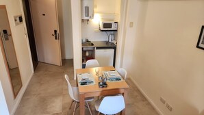 Uma cozinha compacta com micro-ondas, um frigorífico pequeno e uma pia.