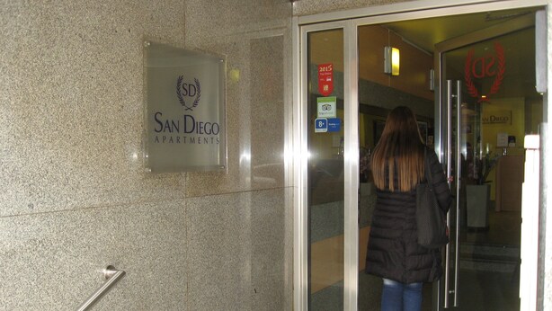 Entrada com porta de vidro para San Diego Apartments, com uma placa indicando ser um hotel 8 estrelas no TripAdvisor.