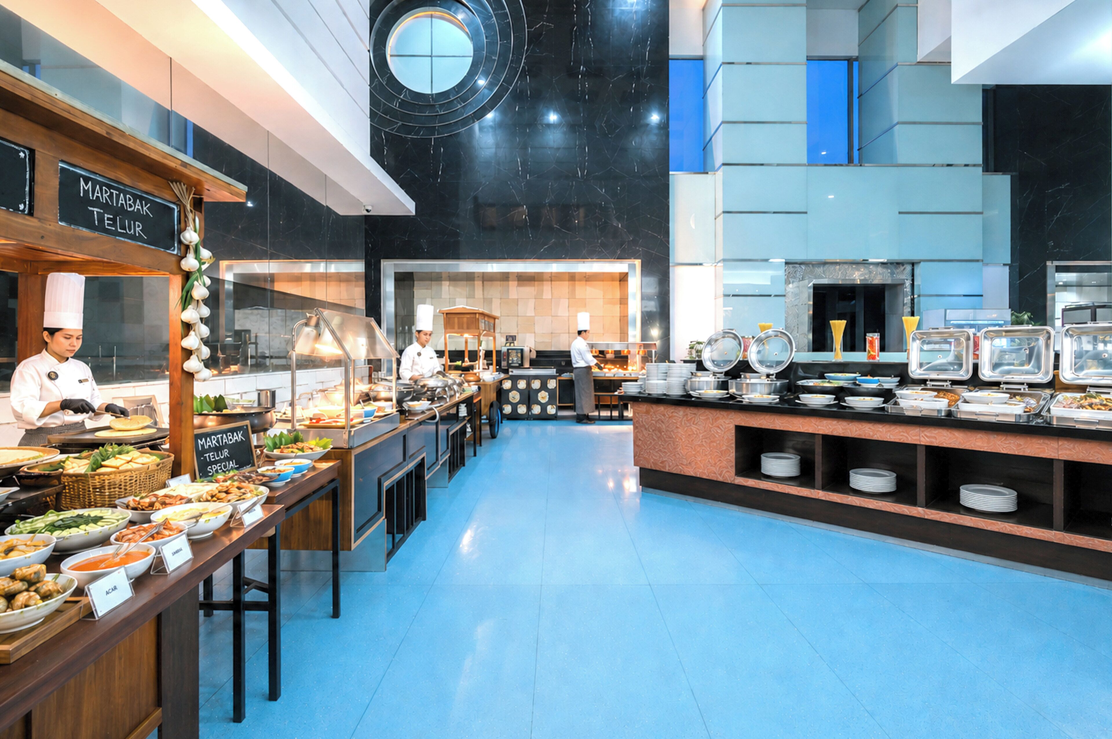 Disposição de buffet com várias estações de comida, chefs a preparar refeições e um design de interiores moderno.