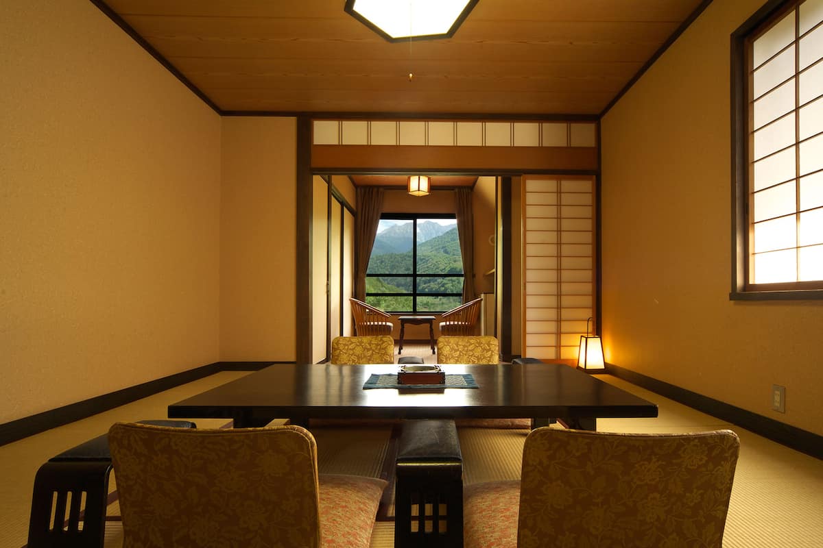Quarto japonês tradicional com tatames, uma mesa baixa e duas cadeiras.