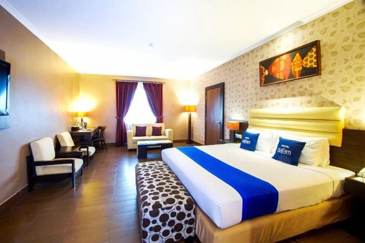 Quarto de hotel com uma cama grande, uma escrivaninha, uma cadeira e um sofá.
