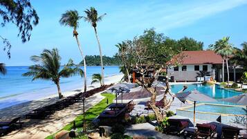 Resort com piscina, praia e palmeiras.