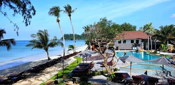 Resort com piscina, praia e palmeiras.