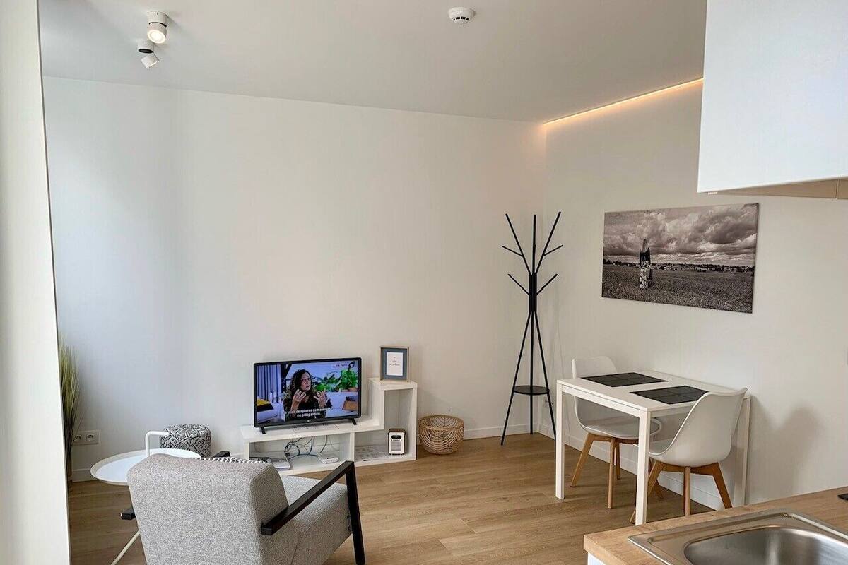 Uma sala de estar moderna com televisão, mesa de jantar e área de cozinha.