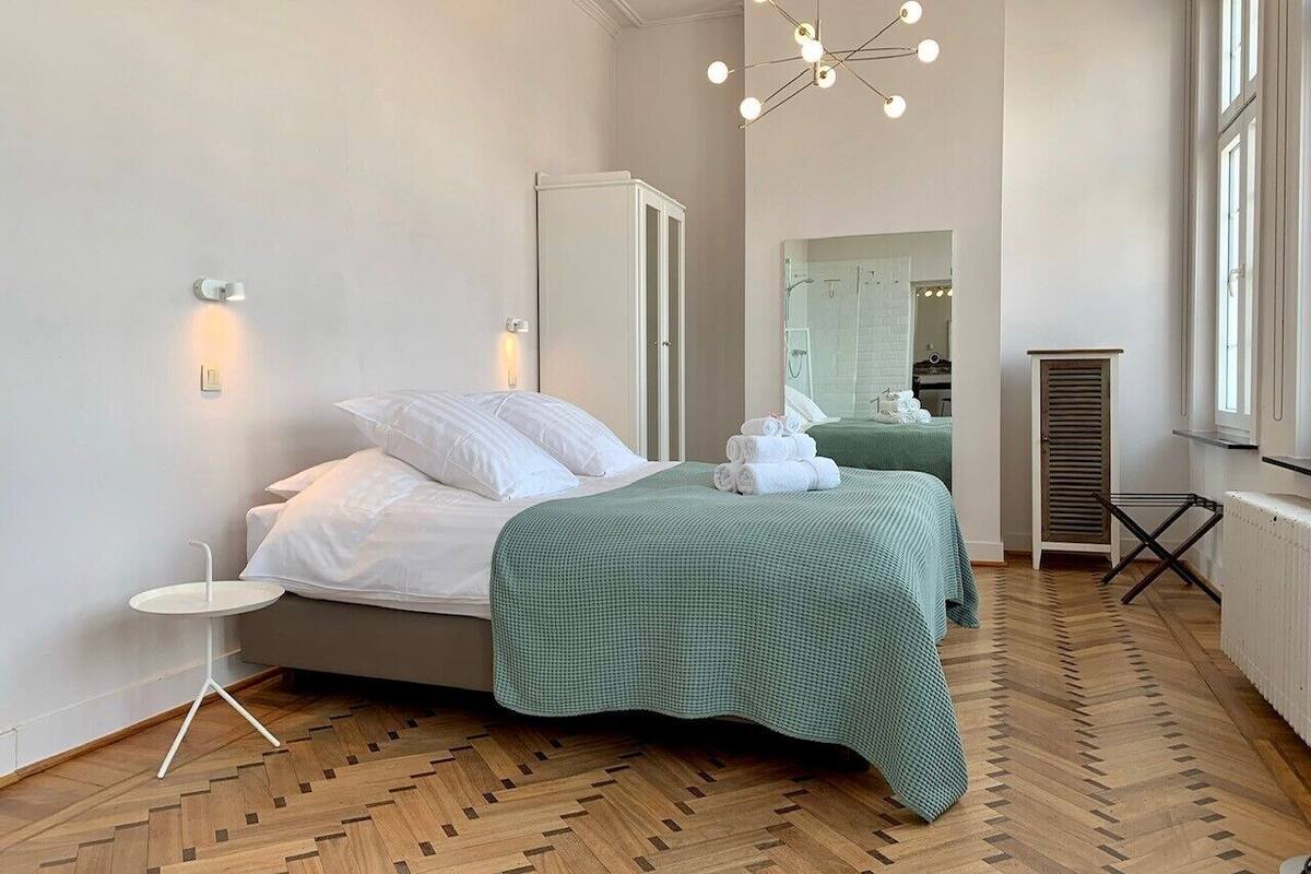 Quarto moderno com cama, mesa de cabeceira e luminária suspensa.