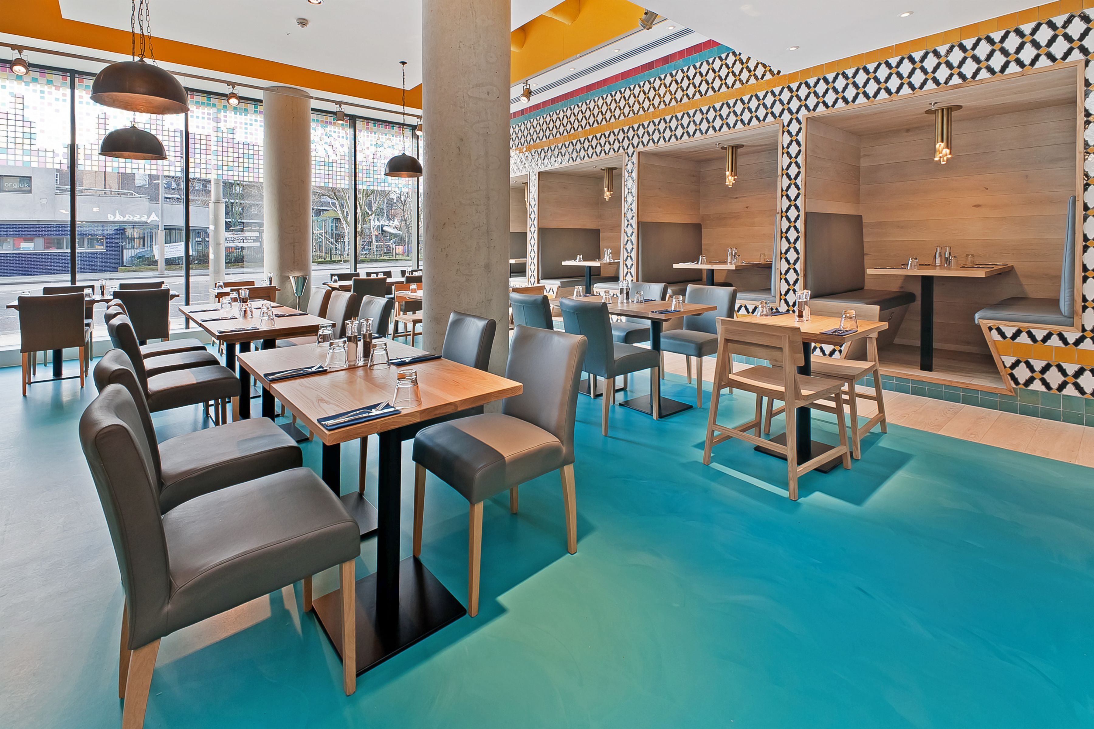 Um restaurante moderno com chão azul, mesas e cadeiras de madeira.