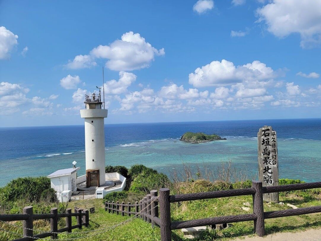 Um farol com vista clara do oceano e uma placa de sinalização em primeiro plano.