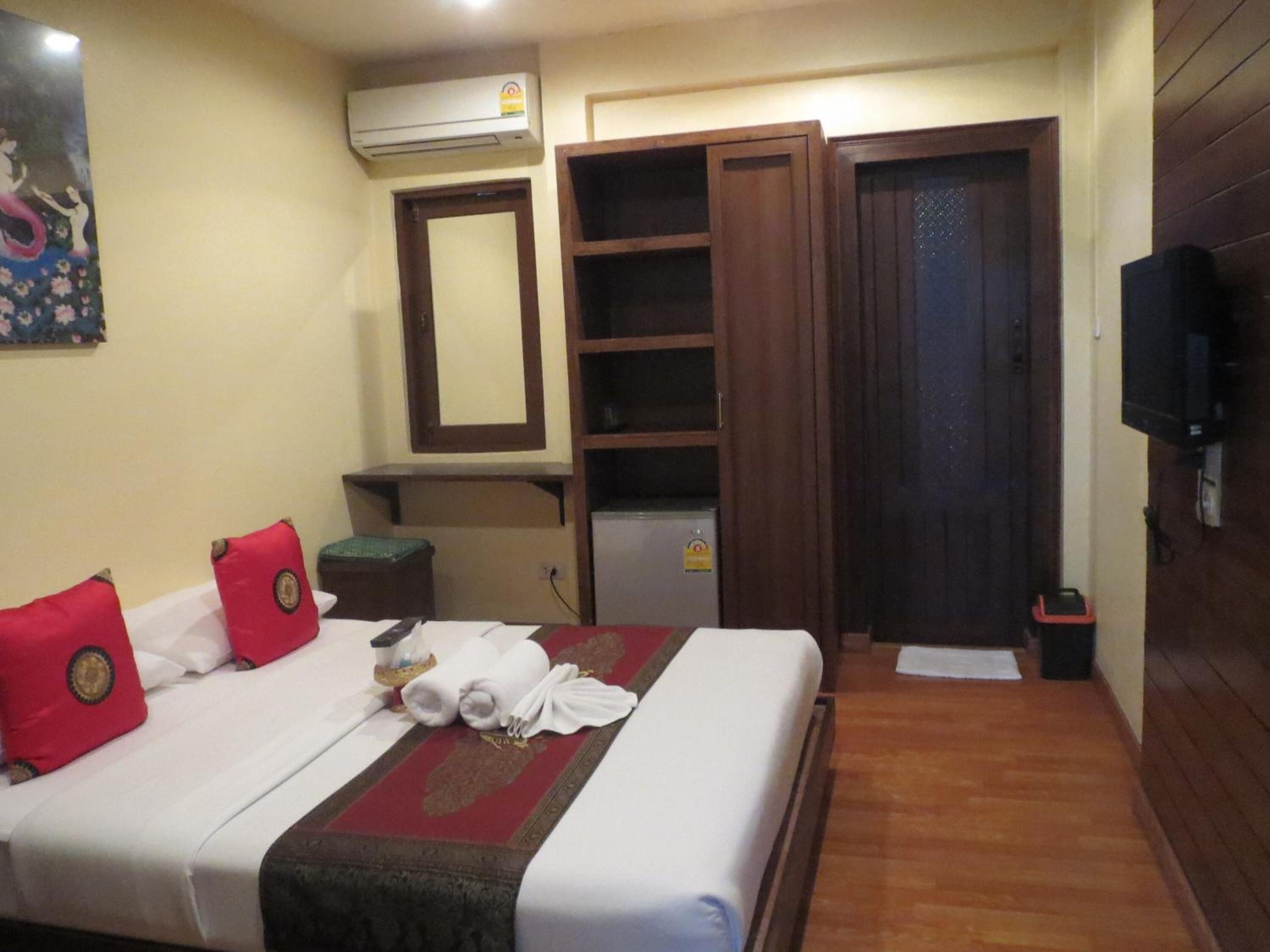 Quarto de hotel com cama, escrivaninha, armário, ar-condicionado e televisão.