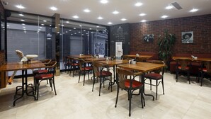 Um restaurante com paredes de tijolo, mesas de madeira e cadeiras vermelhas acolchoadas.