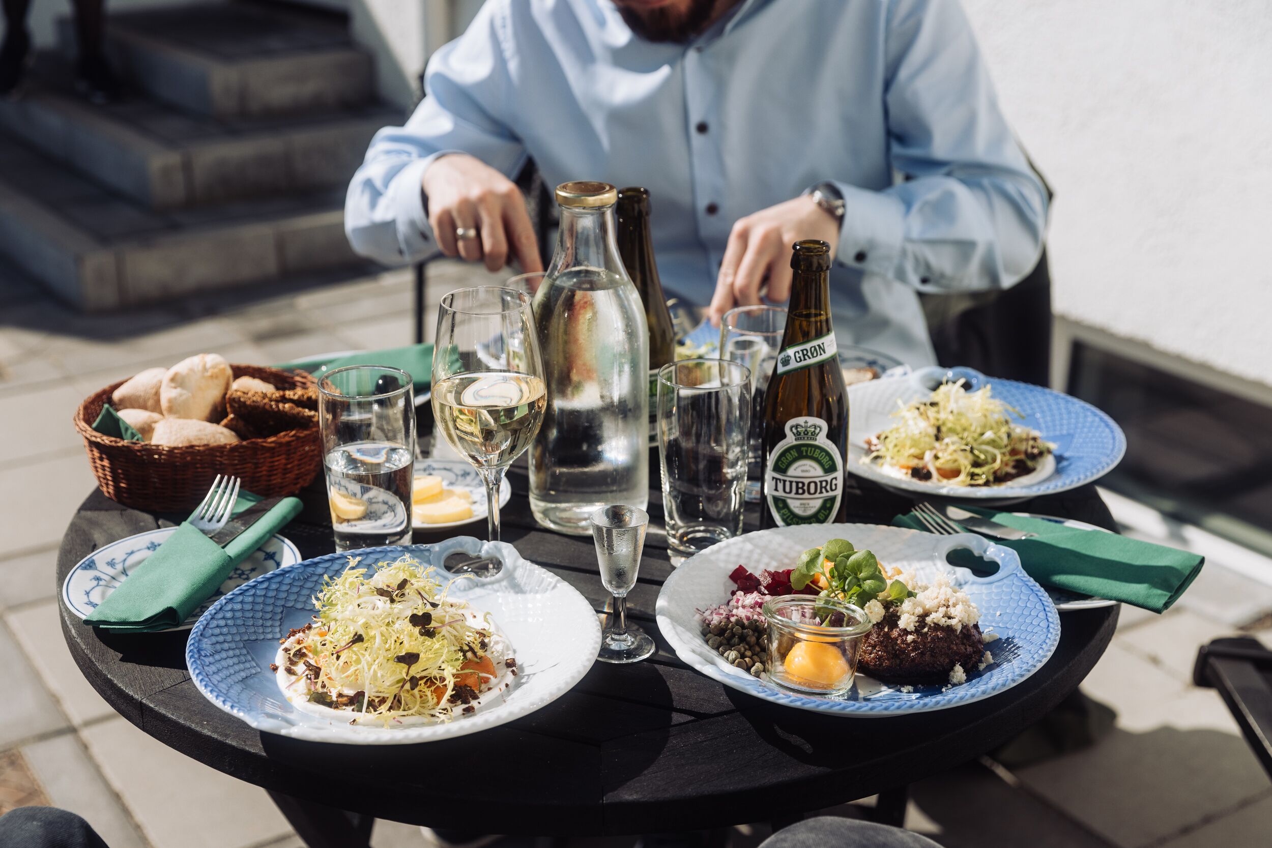 Uma mesa posta com pratos de comida, uma garrafa de vinho e um jarro.