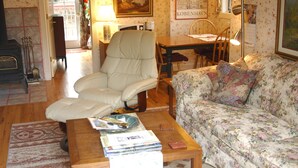 Sala de estar com sofá, poltrona, mesa de centro de madeira e mesa de jantar com cadeiras.