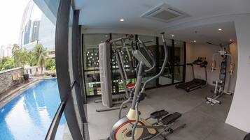 Uma academia com diversos equipamentos de exercício, piscina e vista para a cidade.