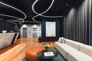 Um hall moderno com balcão de recepção, um sofá, uma mesa de centro e um grande quadro abstrato na parede.