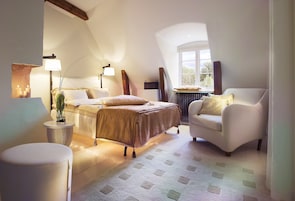 Um quarto aconchegante com cama, mesa de cabeceira, abajur e janela com vista.