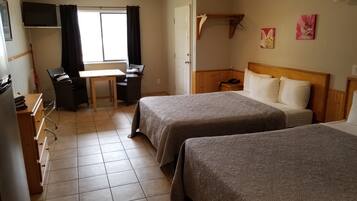 Quarto de hotel com duas camas, uma escrivaninha, uma cadeira, uma televisão e uma janela com cortinas.