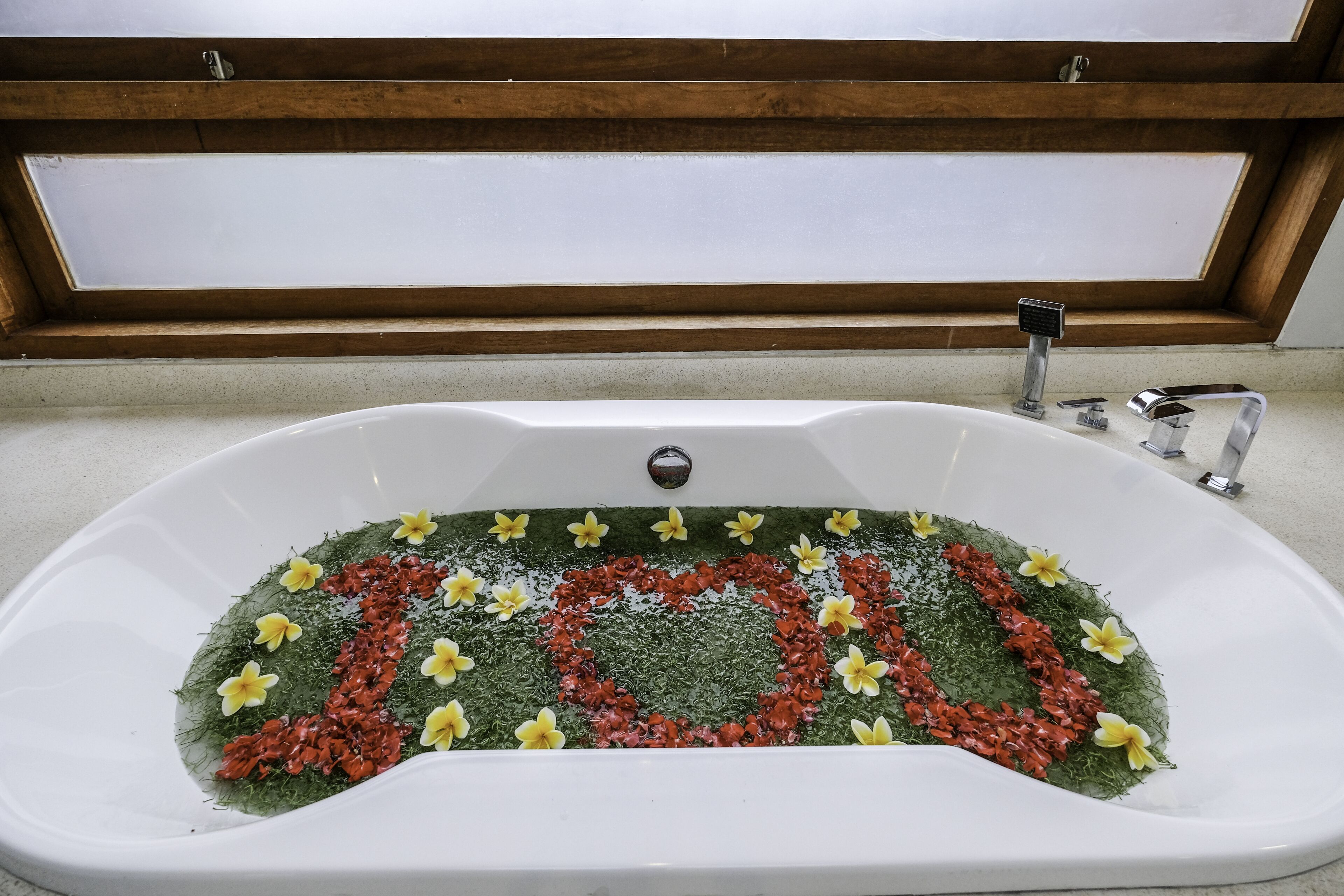 Uma banheira com um arranjo de flores em formato de coração e plantas aquáticas verdes.