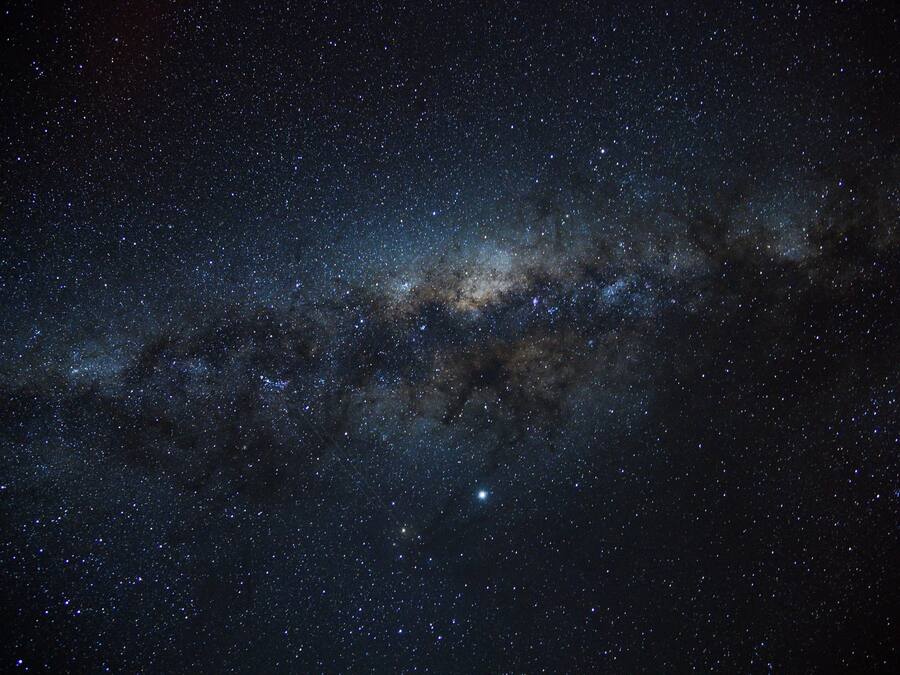 Céu estrelado com uma galáxia visível.