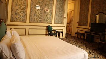 Quarto de hotel com uma cama grande, uma escrivaninha, uma cadeira, uma televisão e um guarda-roupa.
