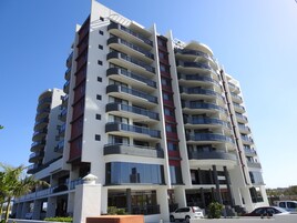 Um hotel com vários andares, varandas, uma loja de jogos e uma área de estacionamento.