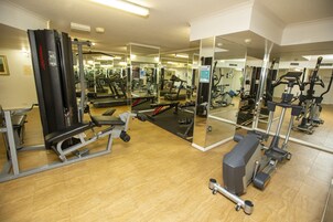 Academia com diversos equipamentos de exercício, incluindo esteiras, aparelhos de musculação e pesos livres.