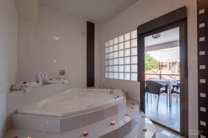 Uma casa de banho moderna com uma banheira grande, zona de duche e porta de vidro que dá para uma área de estar exterior.