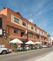 Hotel com fachada de tijolos, área de estar ao ar livre com guarda-sóis e bandeiras.
