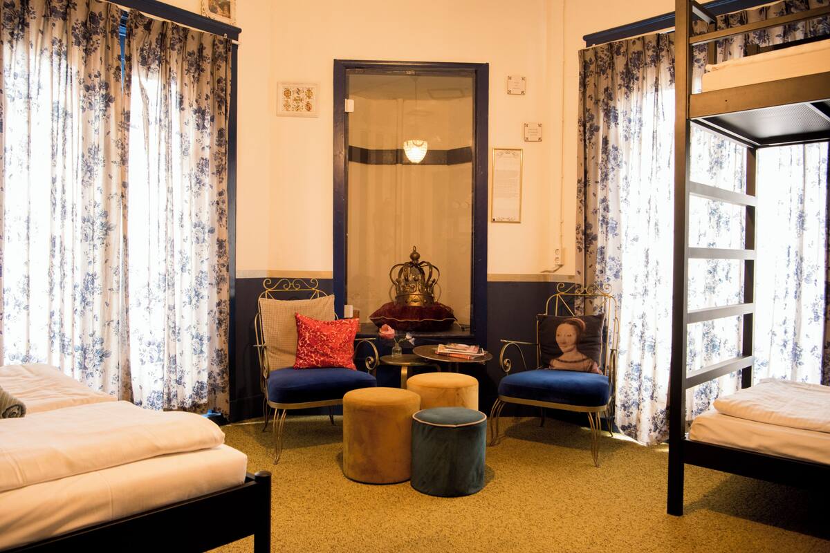 Quarto com duas camas, uma mesa e um objeto decorativo, além de uma cadeira.