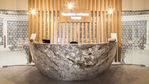 Bancada de recepção com tampo de mármore, ripas de madeira e uma placa com a inscrição 'Mountain wellness lounge'.
