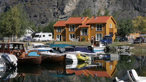 Uma propriedade à beira do lago com casas de madeira, um cais com barcos e um fundo de pedras.