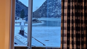 Quarto com porta de vidro deslizante que dá para uma área externa nevada e vista para montanhas.