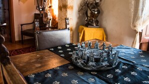 Uma mesa de jantar com um centro de mesa de metal, uma cadeira, um abajur e um vaso com ramos.