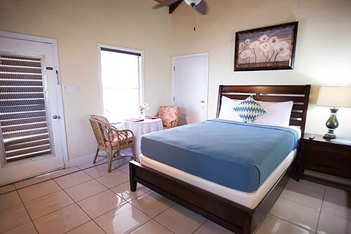 Quarto com cama, cadeira, escrivaninha, luminária e ventilador de teto.