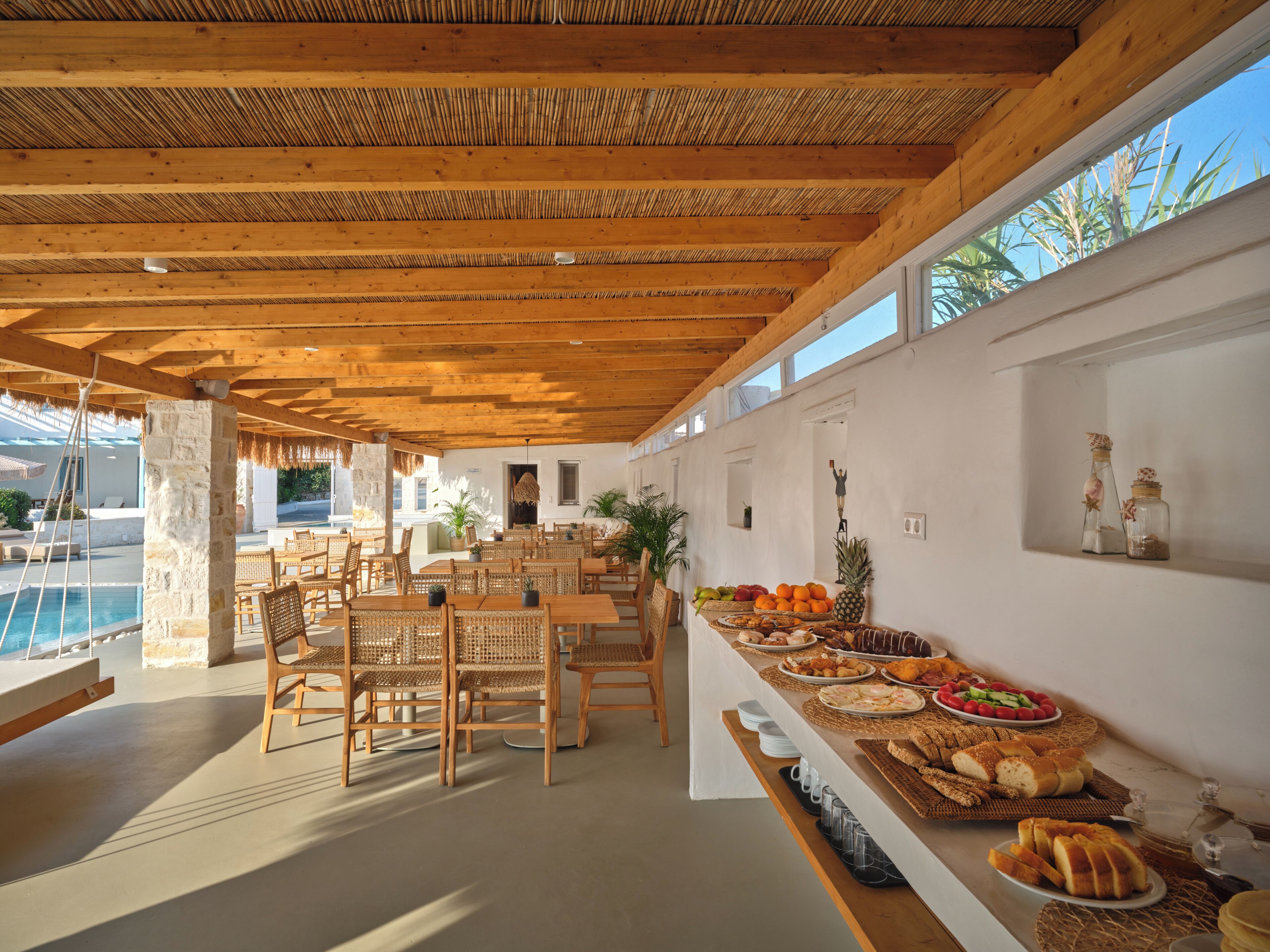 Uma ampla área de refeições ao ar livre com móveis de madeira e uma mesa de buffet.