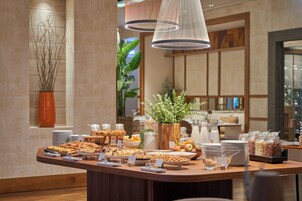 Disposição de buffet com diversos alimentos e um arranjo de plantas decorativo.