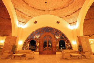 Um lobby com entrada em arco imponente, área de estar e teto de tijolos.