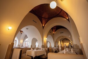 Um restaurante com tetos em arco e mesas preparadas para refeições.