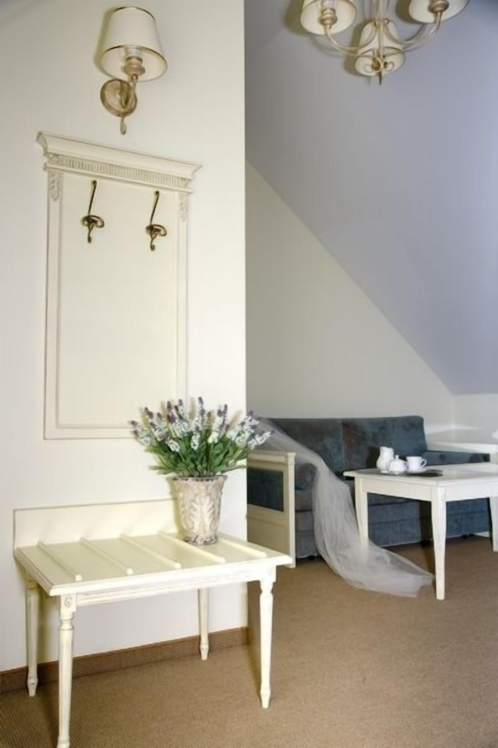 Um quarto com um banco branco, um sofá azul, uma mesa branca e um candelabro.