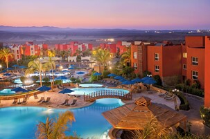Um resort com piscina, espreguiçadeiras e palmeiras.