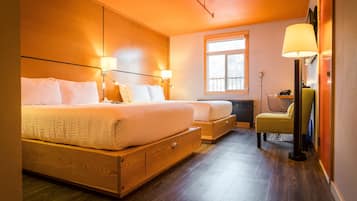 Quarto de hotel moderno com uma cama grande, mesas de cabeceira, uma escrivaninha e uma cadeira.