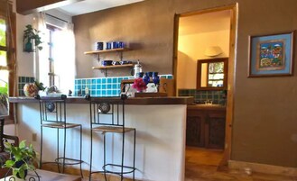 Uma cozinha com bancada, janela e porta que dá para outro cômodo.